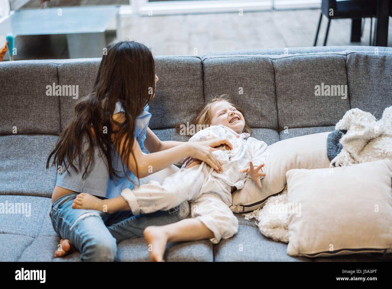 two sisters playing together on the big couch Stock Photo - Alamy