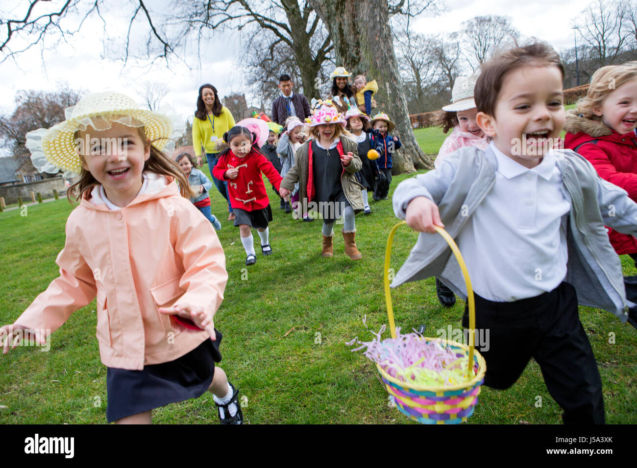 Nursery children running across a field during their outdoor Easter egg ...
