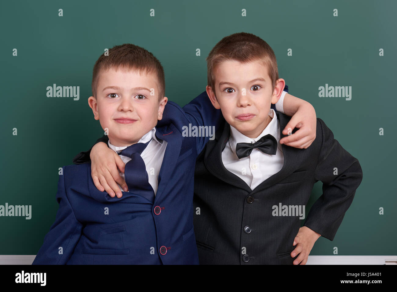 two friends, elementary school boy near blank chalkboard background ...