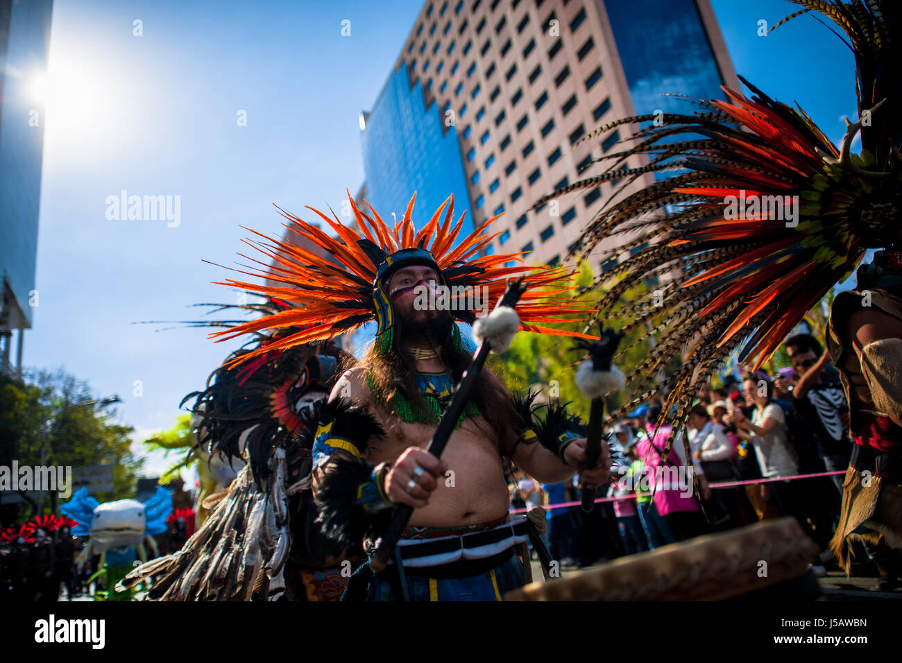 A Mexican man, wearing a colorful feather headgear inspired by Aztecs ...