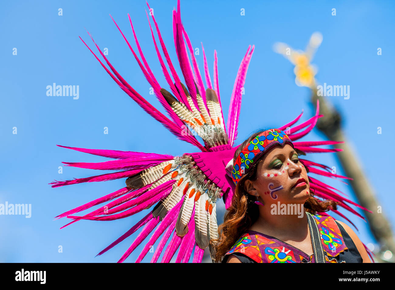 A Mexican woman, wearing a large feather headgear inspired by Aztecs ...
