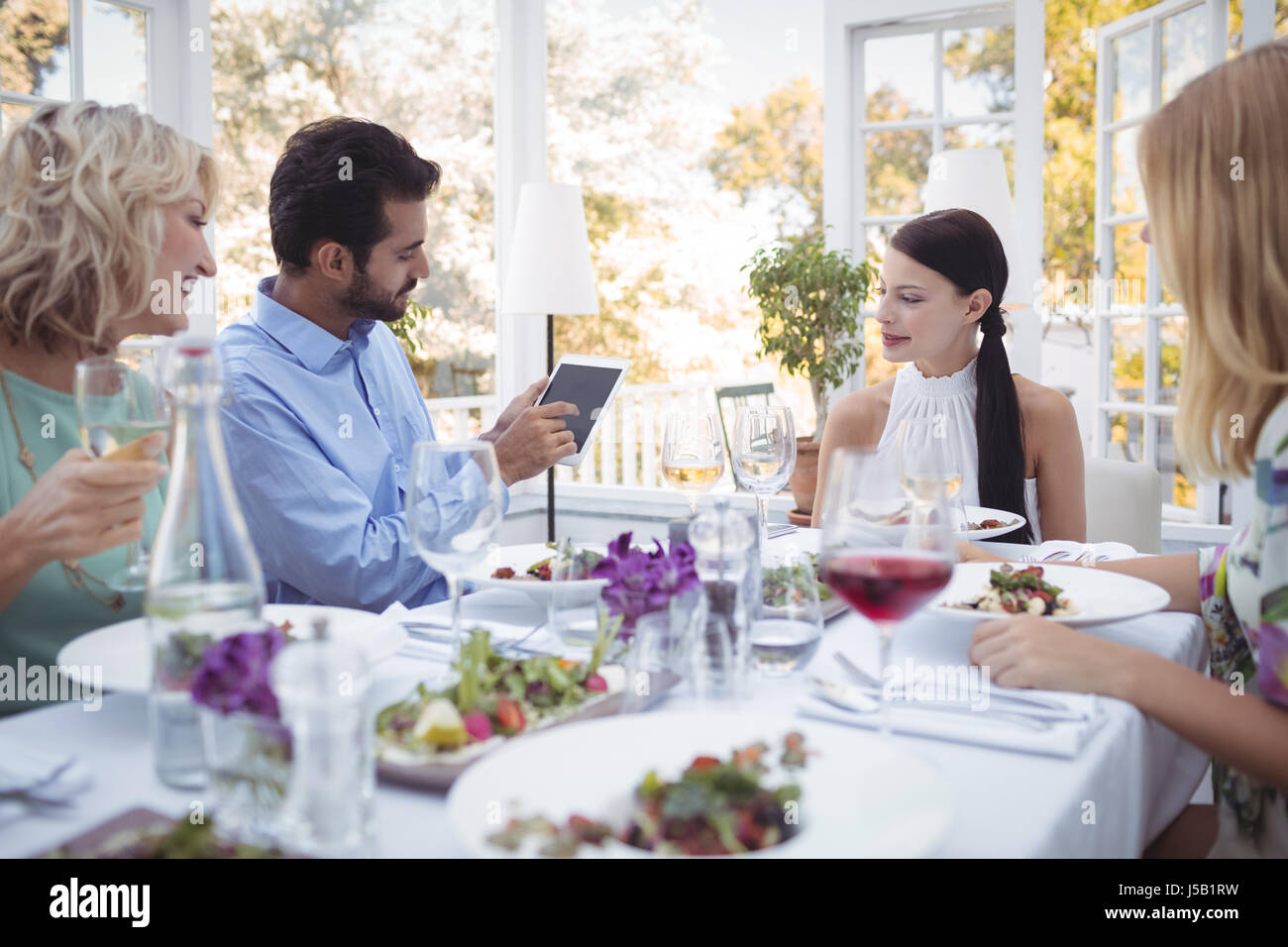 Group of friends interacting with each other while having meal together ...