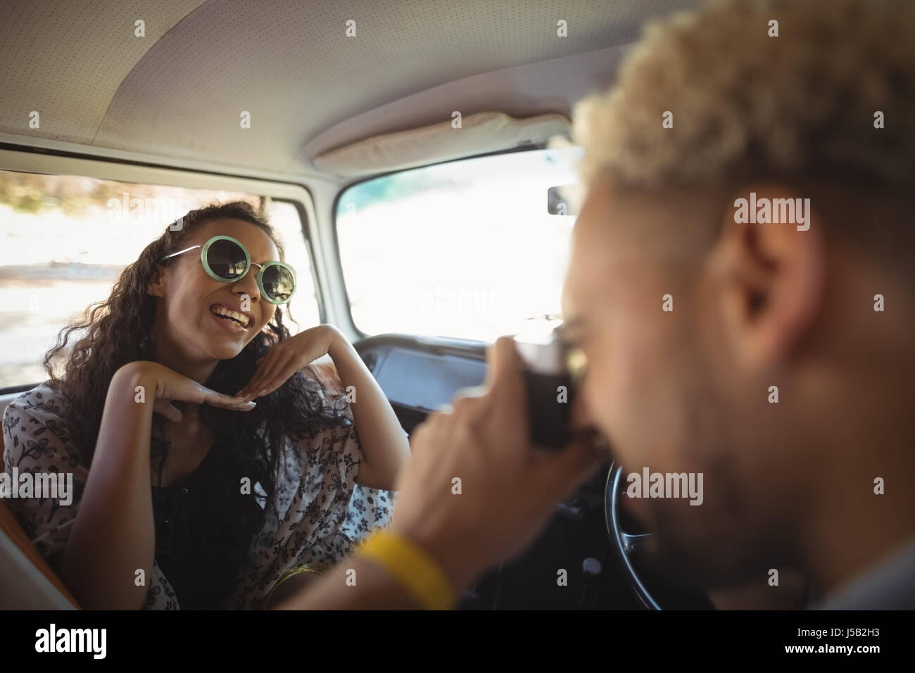 Man photographing woman from camera while traveling in van Stock Photo ...