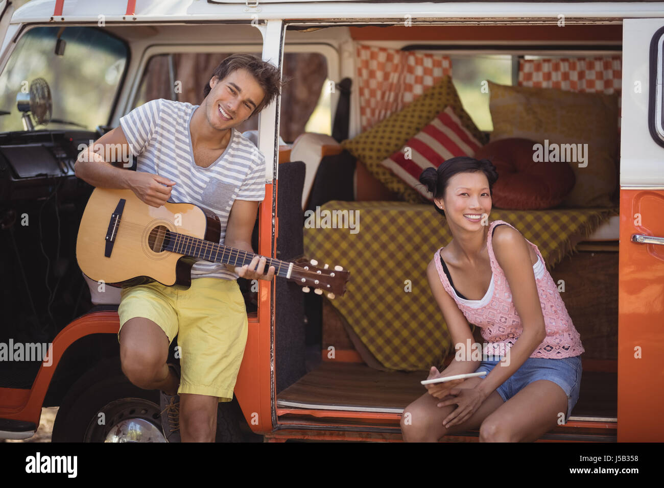 Portrait of happy friends enjoying while sitting in motor home at ...