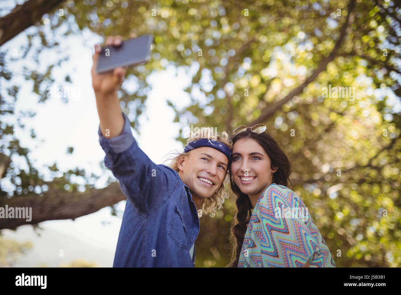 Happy couple taking selfie against trees at forest Stock Photo - Alamy