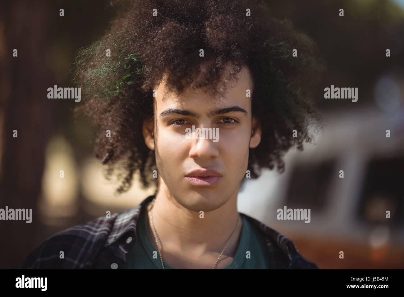Portrait of young man with curly hair against van Stock Photo - Alamy