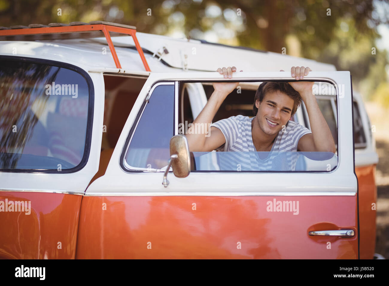 Portrait of cheerful young man leaning on van at forest Stock Photo - Alamy