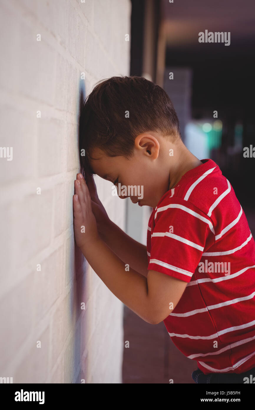 Side view of sad boy leaning on wall at school building Stock Photo - Alamy