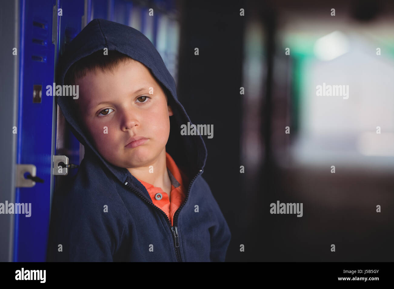 Portrait of sad boy leaning on locker at school Stock Photo - Alamy