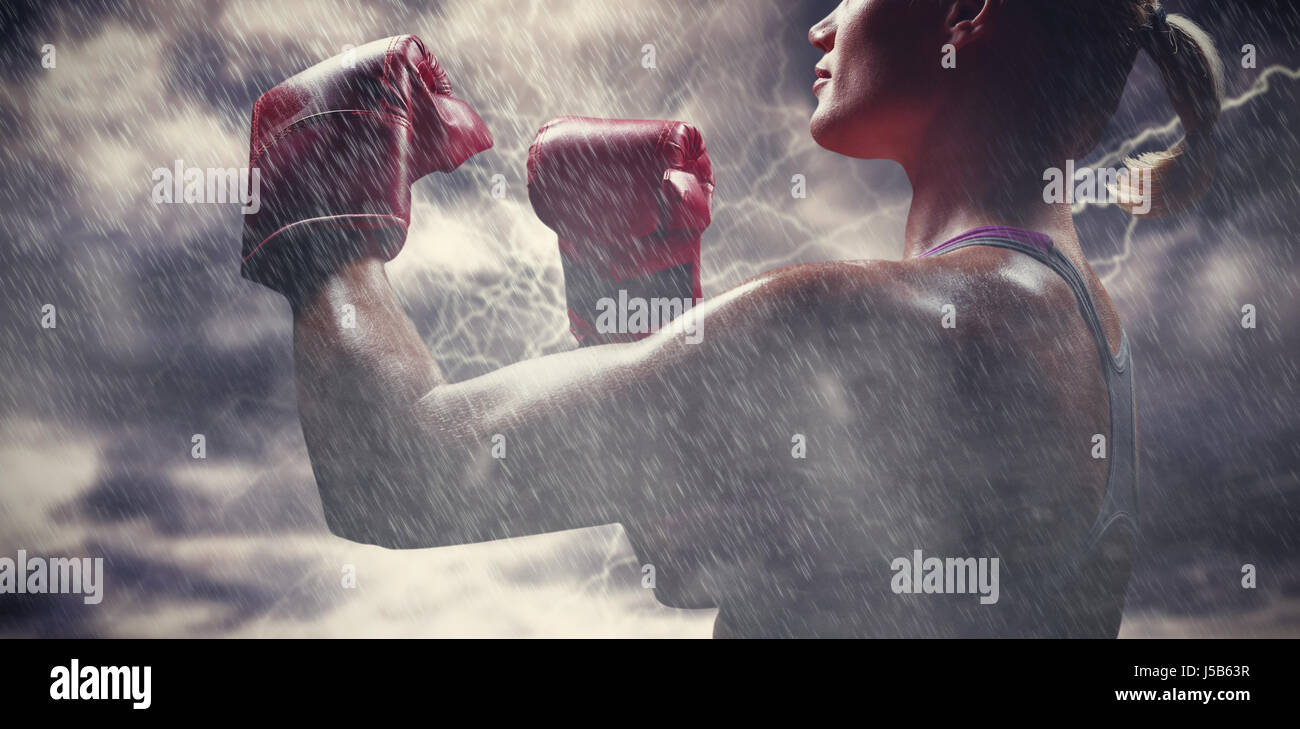 Side view of female boxer with fighting stance against splashing of ...