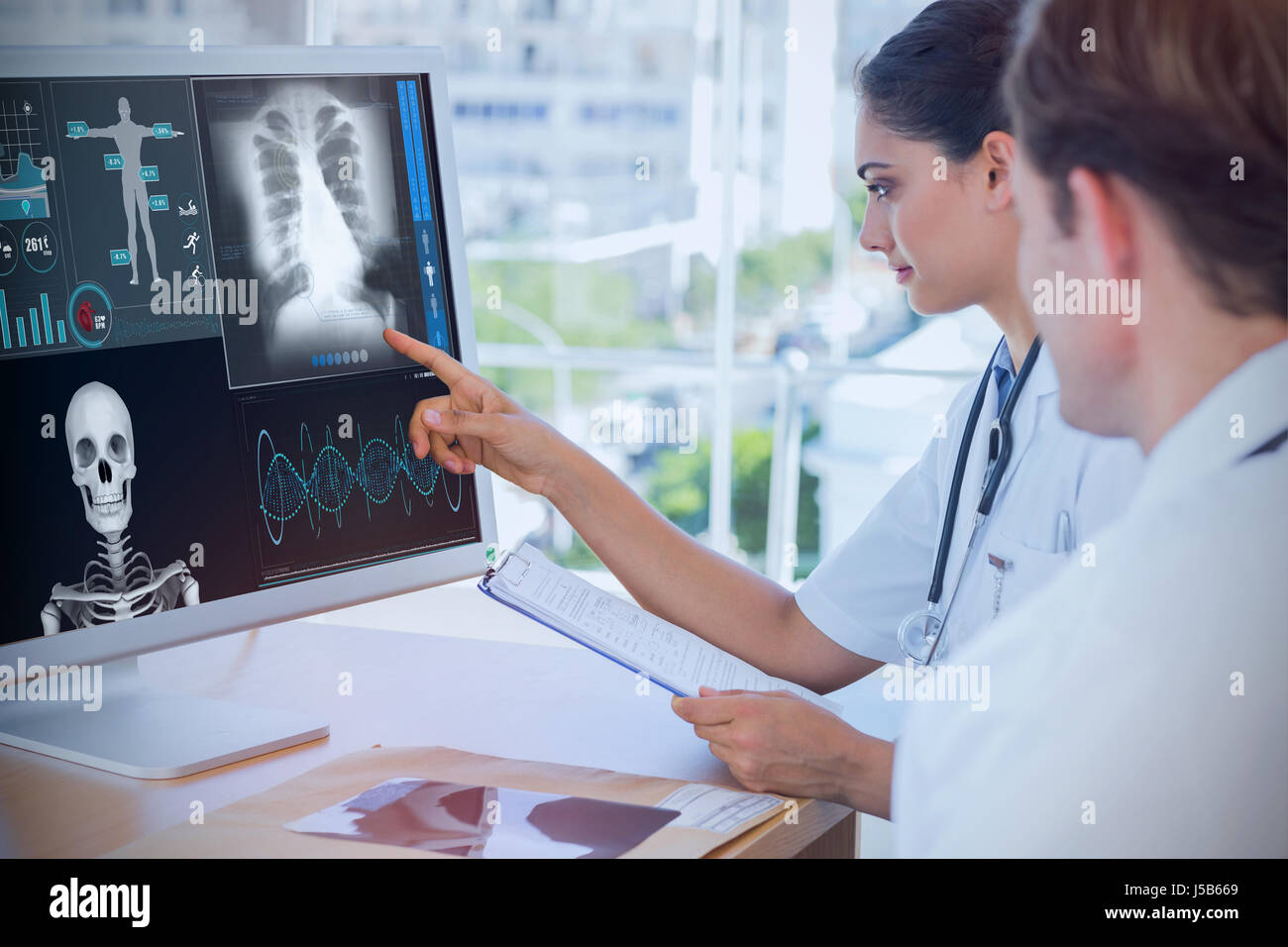 Doctor pointing at the screen of a computer against human skeleton with ...