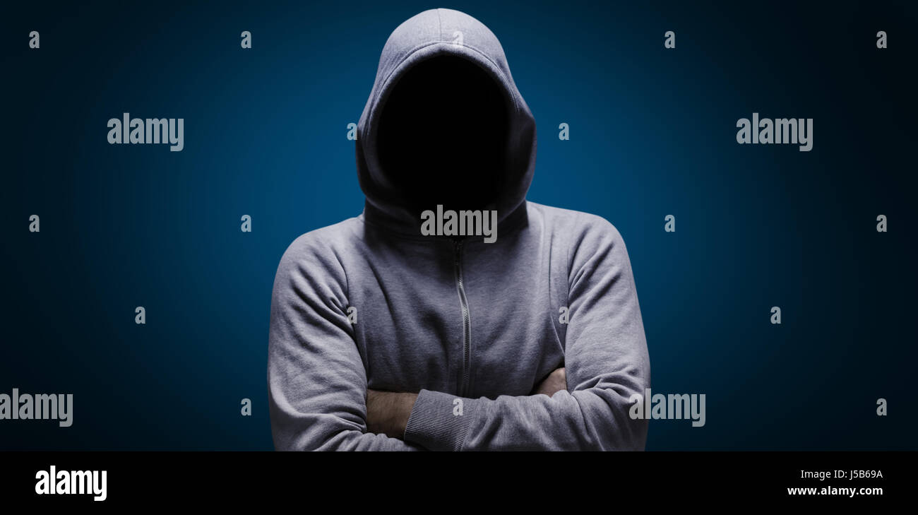 Hacker standing with arms crossed against blue background with vignette ...