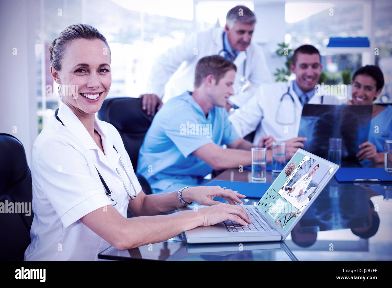 Beautiful smiling doctor typing on keyboard with her team behind ...