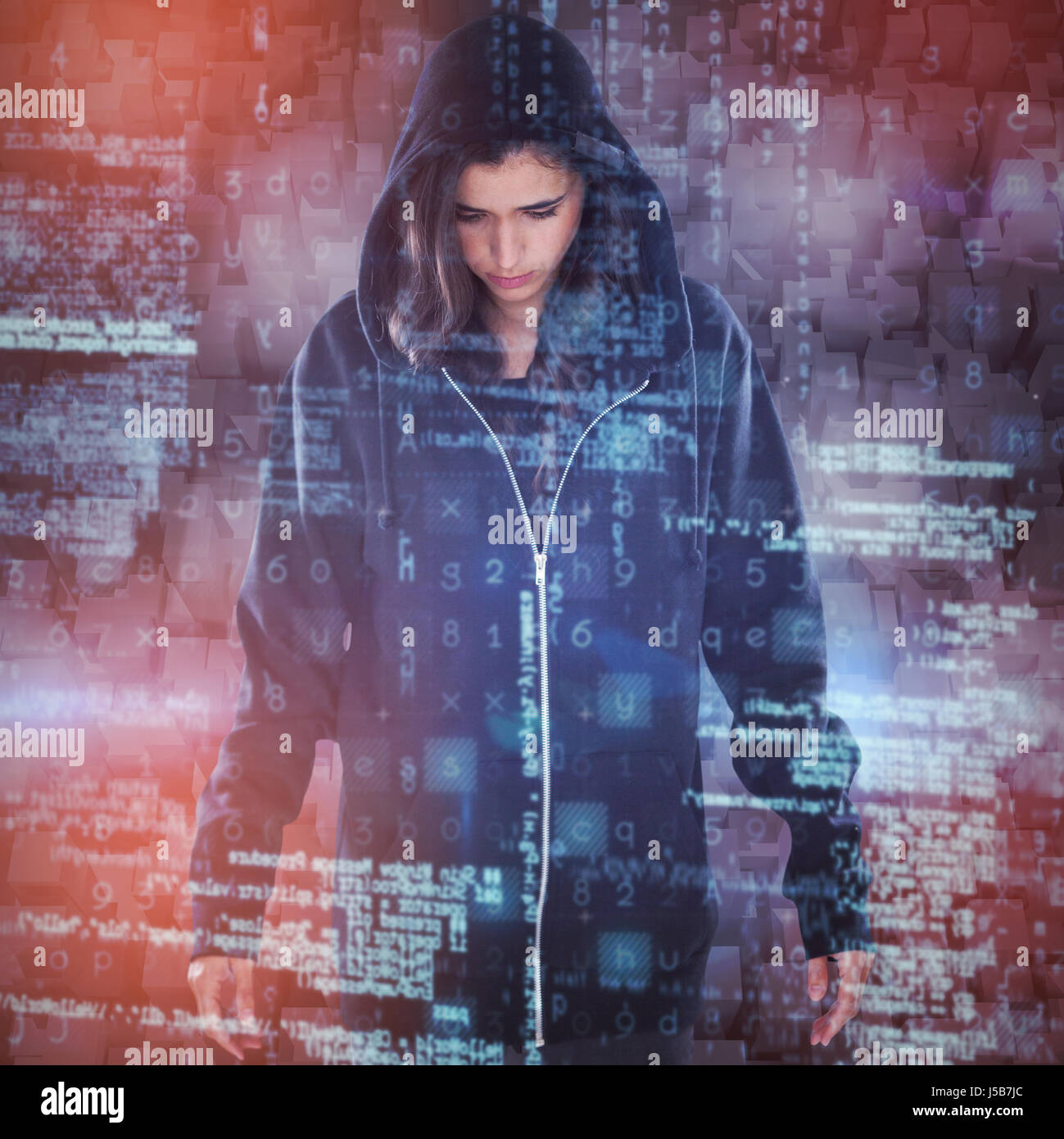 Young female hacker in black hoodie standing against graphic image of ...