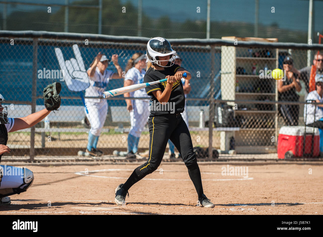 Teenage batter in black softball uniform swinging at a fastball Stock ...