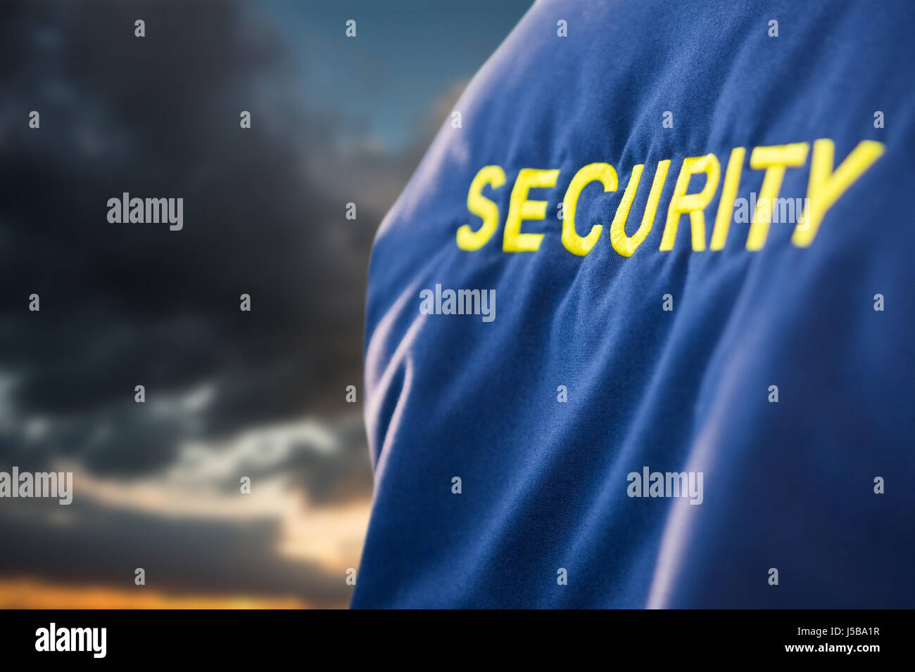 SECURITY text on uniform against blue and orange sky with clouds Stock ...