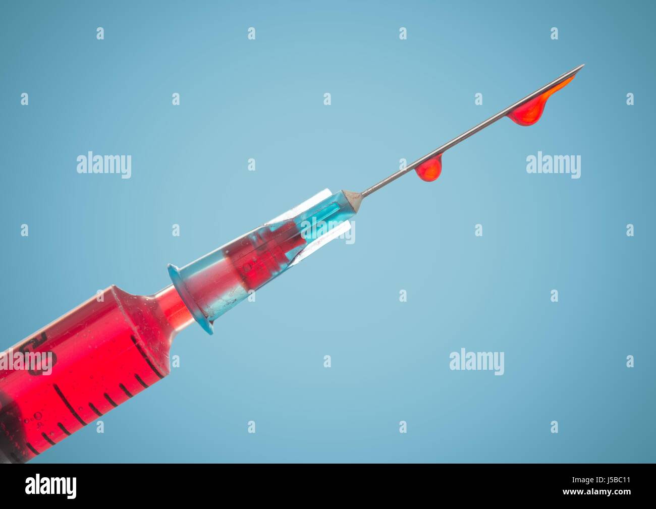 Digital composite of Syringe with red liquid against blue background ...