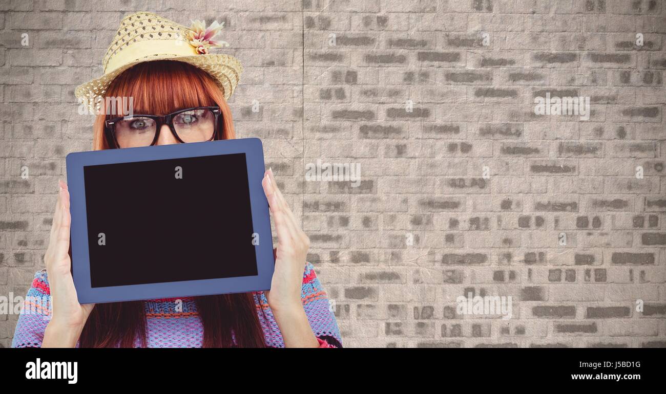 Digital composite of Female hipster showing blank device against wall ...