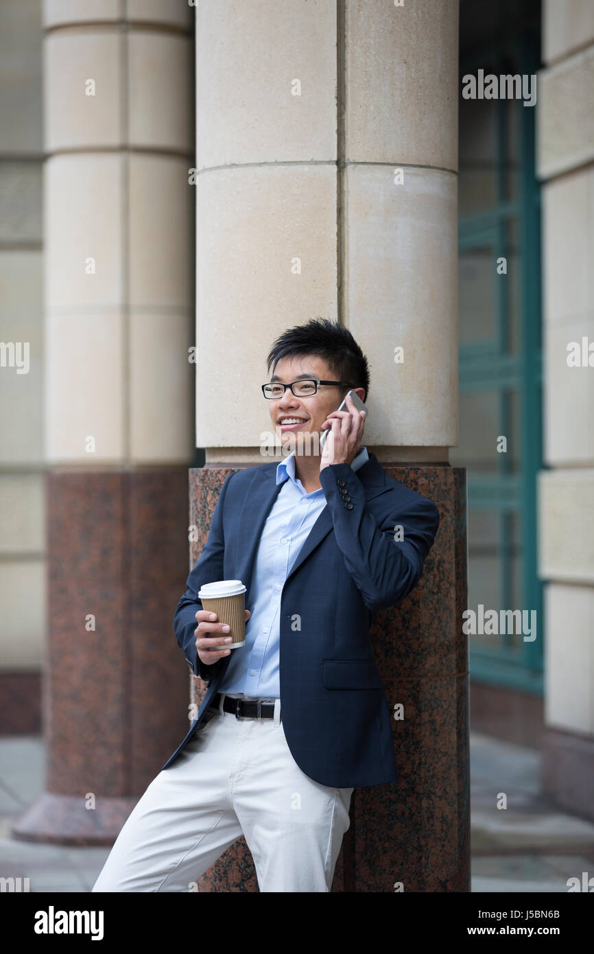 Chinese business Man using his Smart phone outdoors in modern city ...