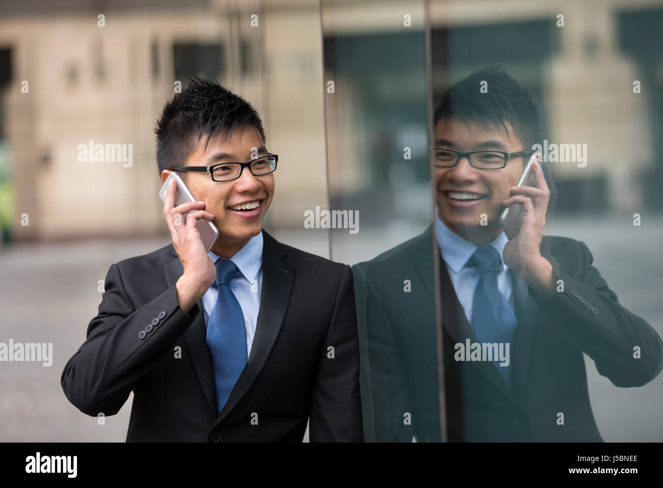 Chinese business Man using his Smart phone outdoors in modern city ...