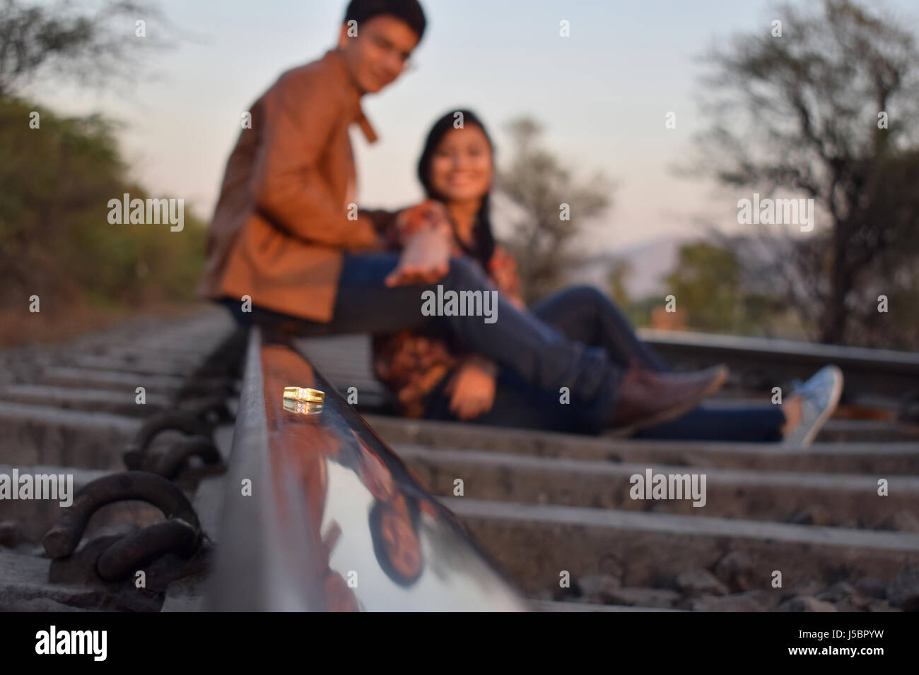Couple sitting on railway track and looking at wedding ring, Pune ...