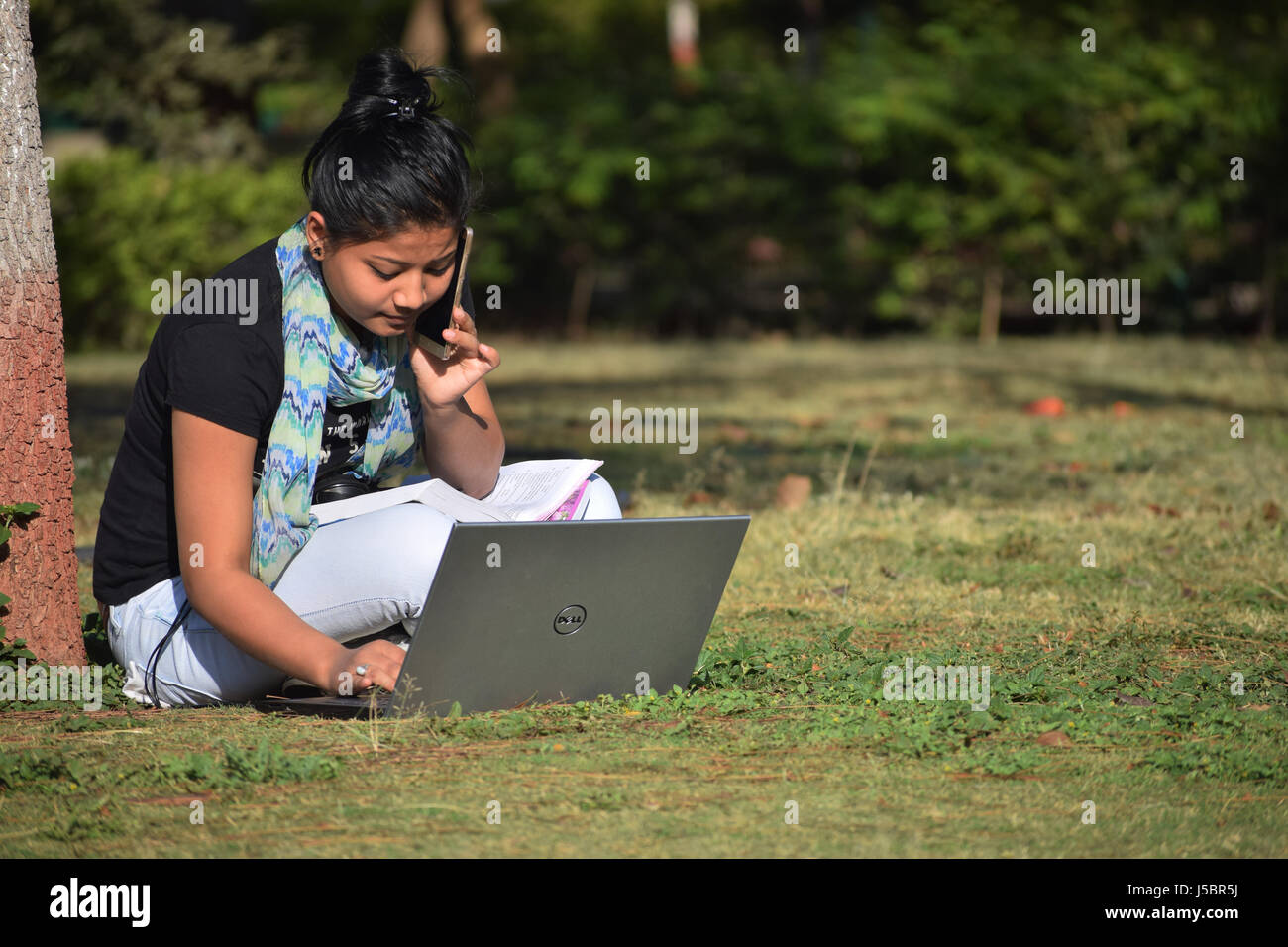 Young girl student studying outside in the garden and talking with ...