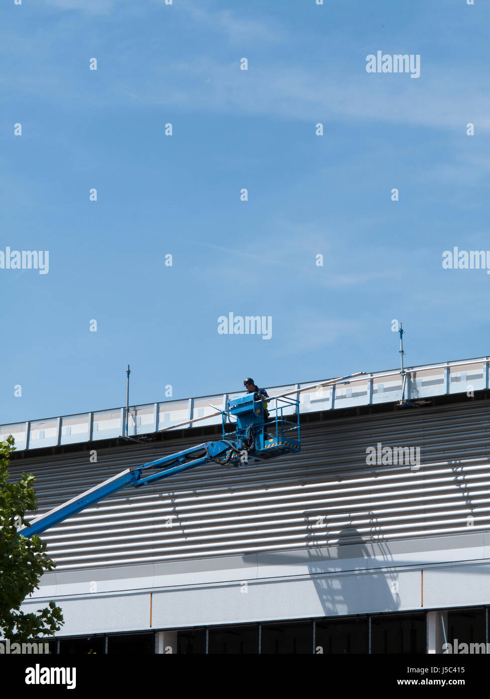 construction workers on mobile access platform installing on cladding ...