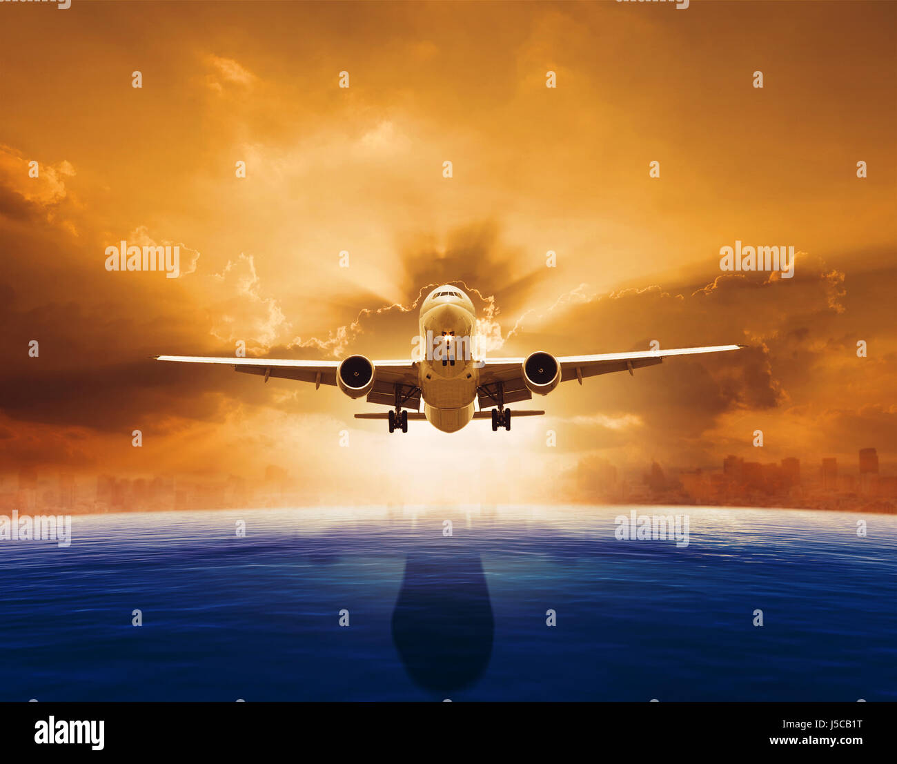 passenger jet plane flying over beautiful sea level with sun set sky ...