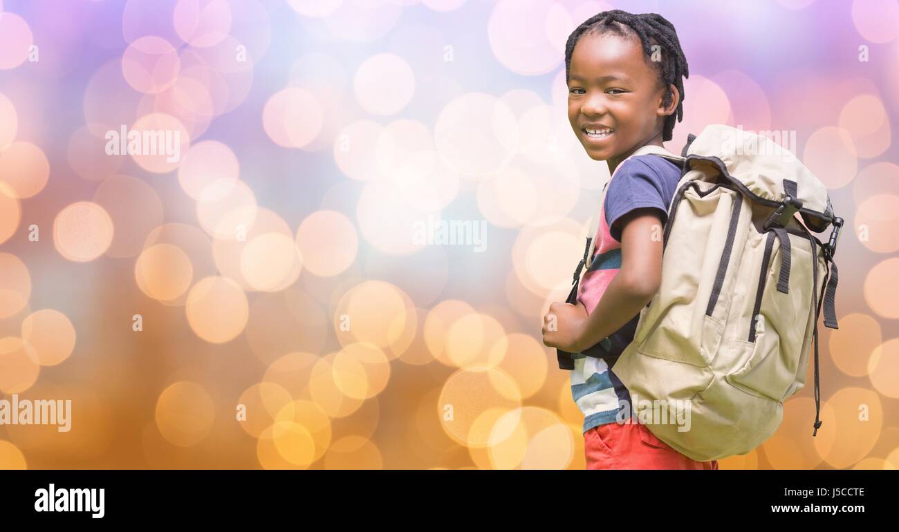 Digital composite of Portrait of happy boy carrying backpack over bokeh ...
