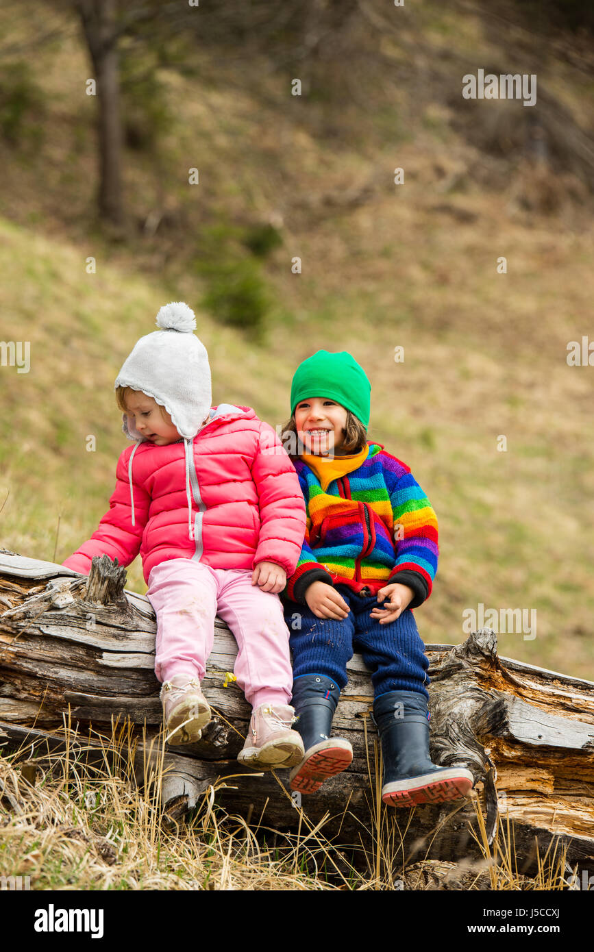 Happy two little kids friends siiting together on tree trunk Stock ...