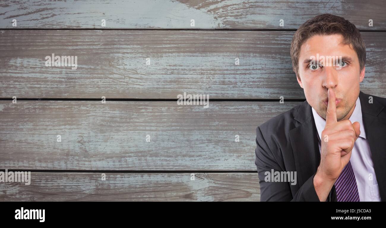 Digital composite of Businessman with finger on lips over wooden wall ...