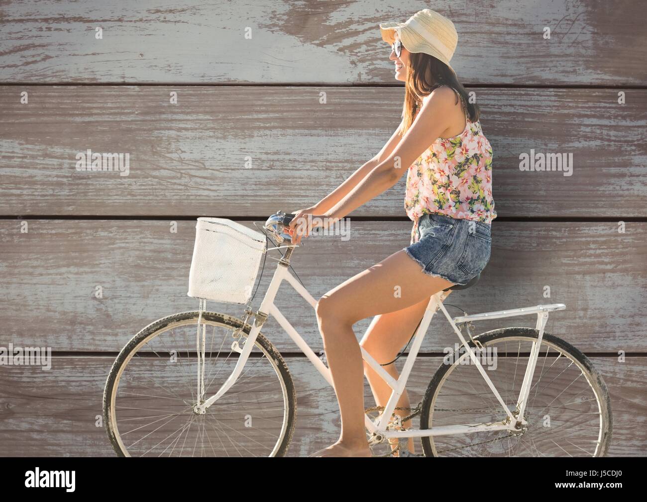 Digital composite of Side view of female riding cycle against wooden ...