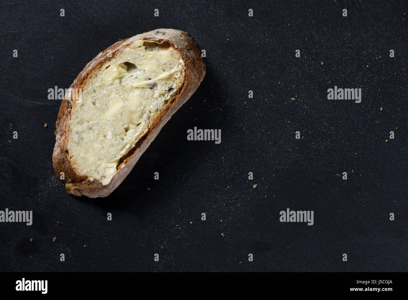A slice of bread loaf on a Black Slate Board Stock Photo - Alamy