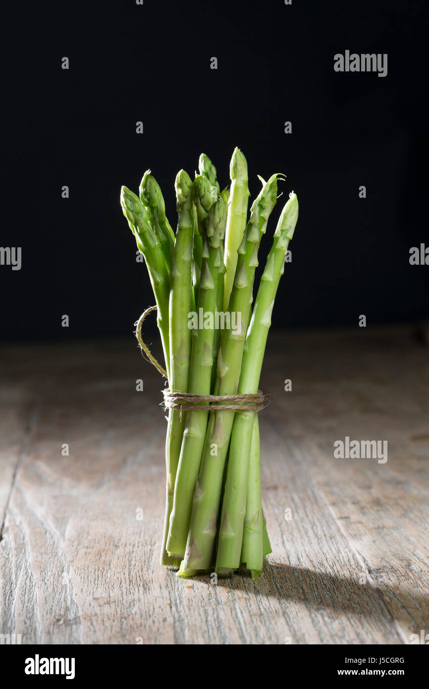 A bunch of fresh asparagus sitting on a rustic wooden table Stock Photo ...
