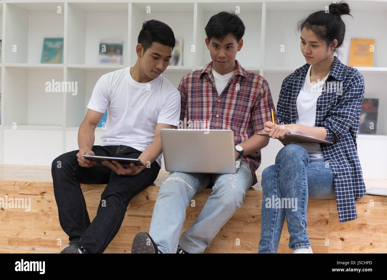young asian people are using different gadgets and smiling, sitting ...
