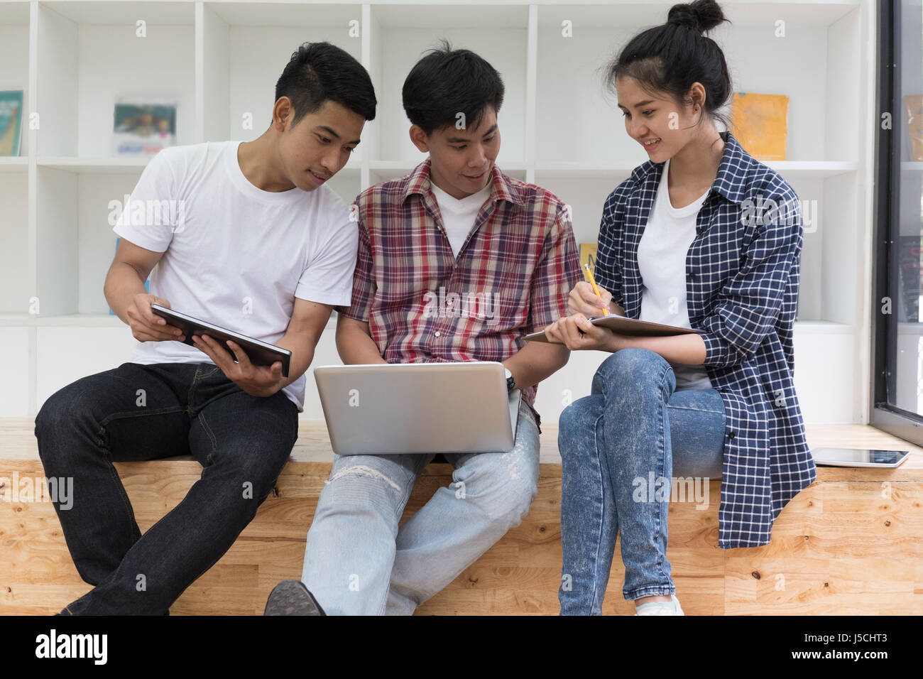 young asian people are using different gadgets and smiling, sitting ...