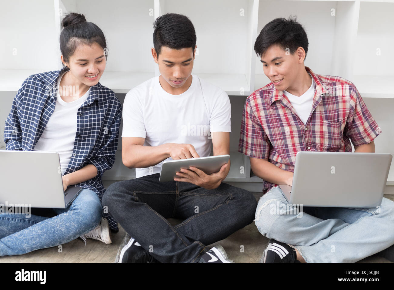 young asian people are using different gadgets and smiling, sitting ...