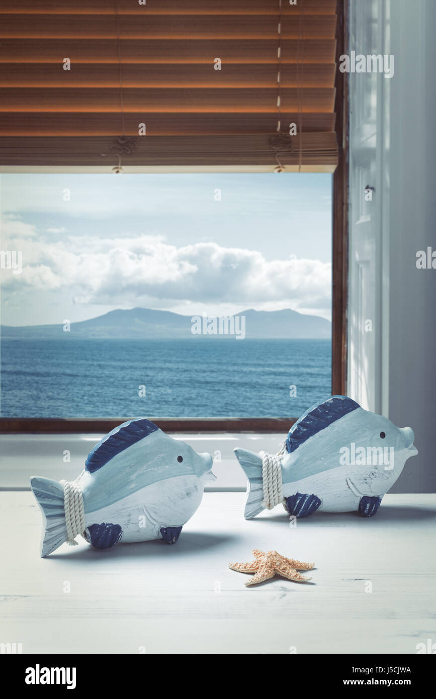 Two wooden fish ornaments sitting in the window overlooking the sea ...