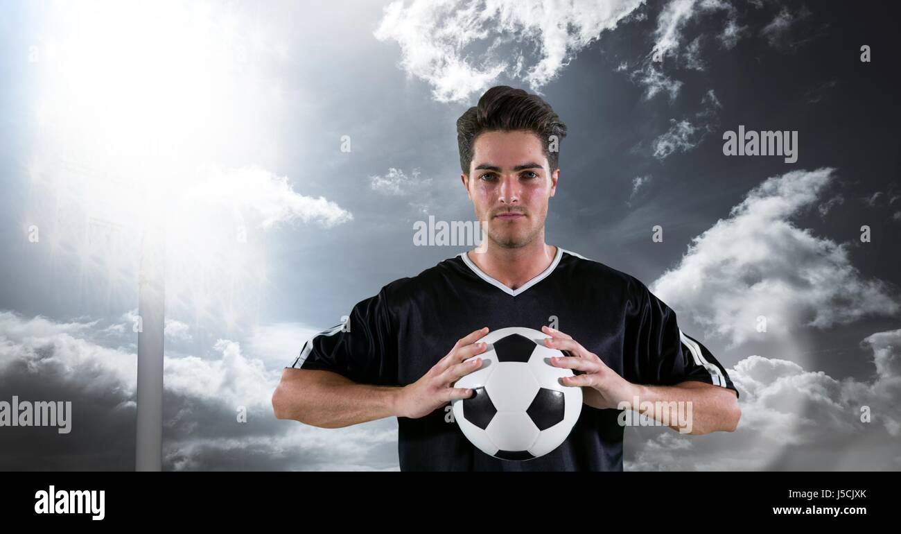 Digital composite of Confident player holding soccer ball against sky ...