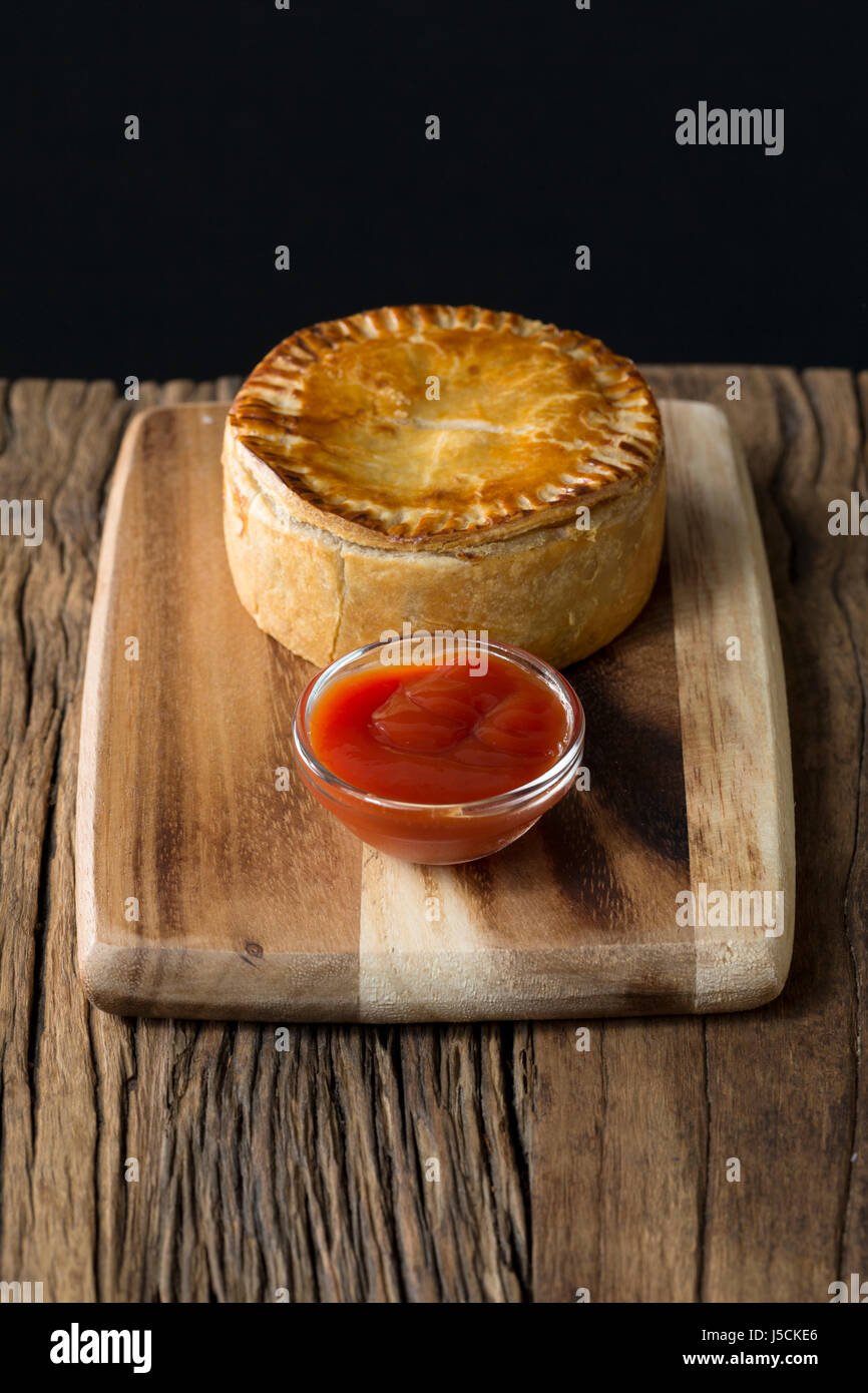 A Traditional British meat pie sitting on a rustic wooden table Stock ...