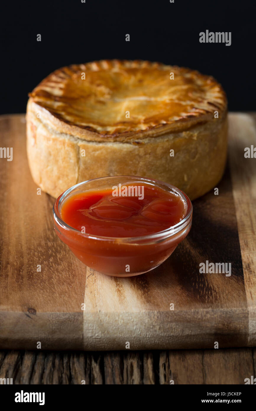 A Traditional British meat pie sitting on a rustic wooden table Stock ...