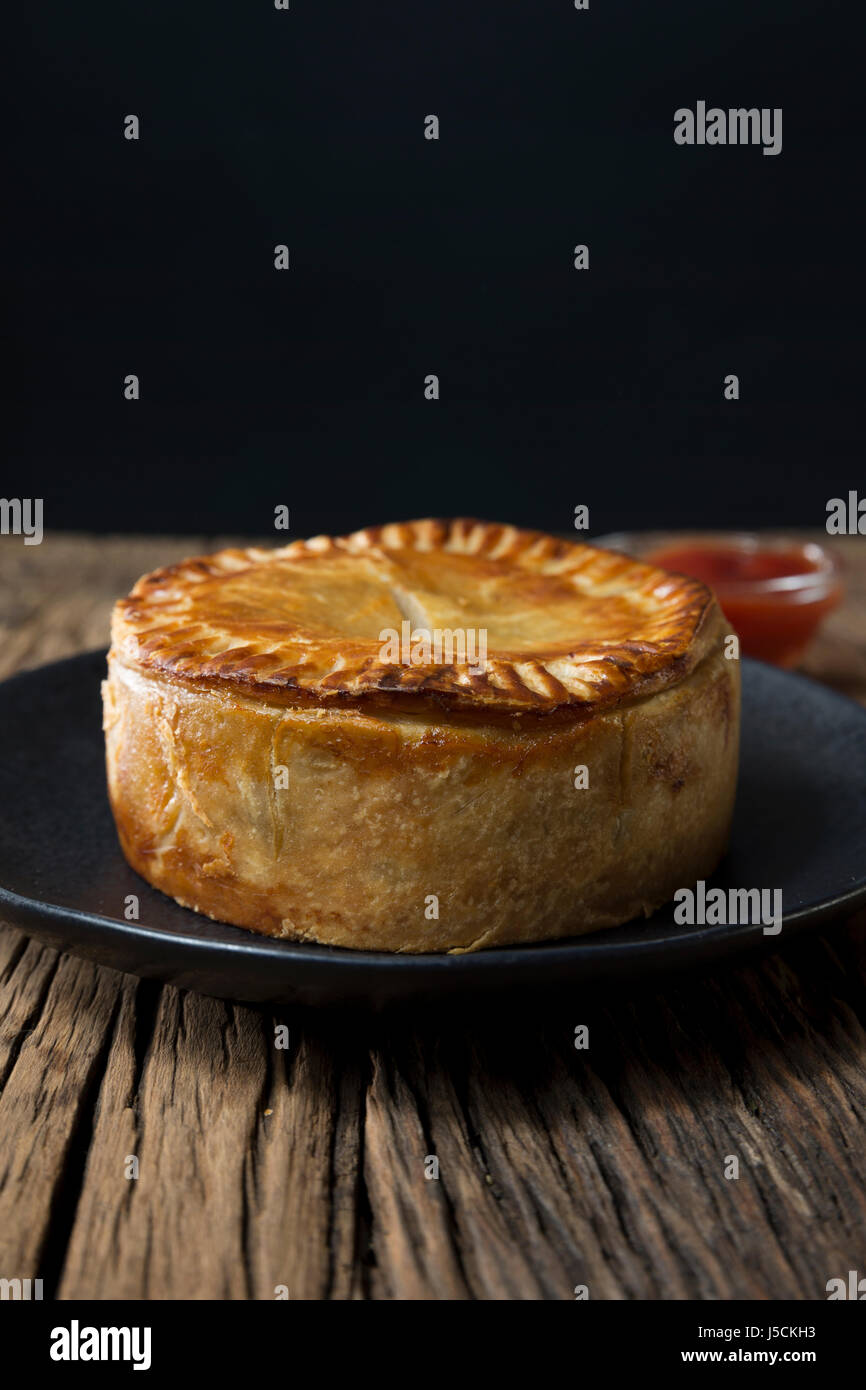 A Traditional British meat pie sitting on a rustic wooden table Stock ...