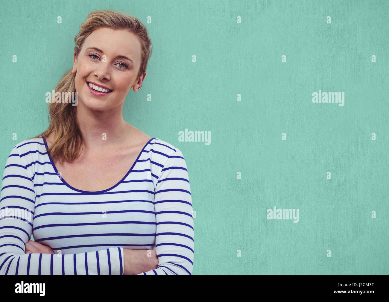 Digital composite of Smiling woman with arms crossed over turquoise ...