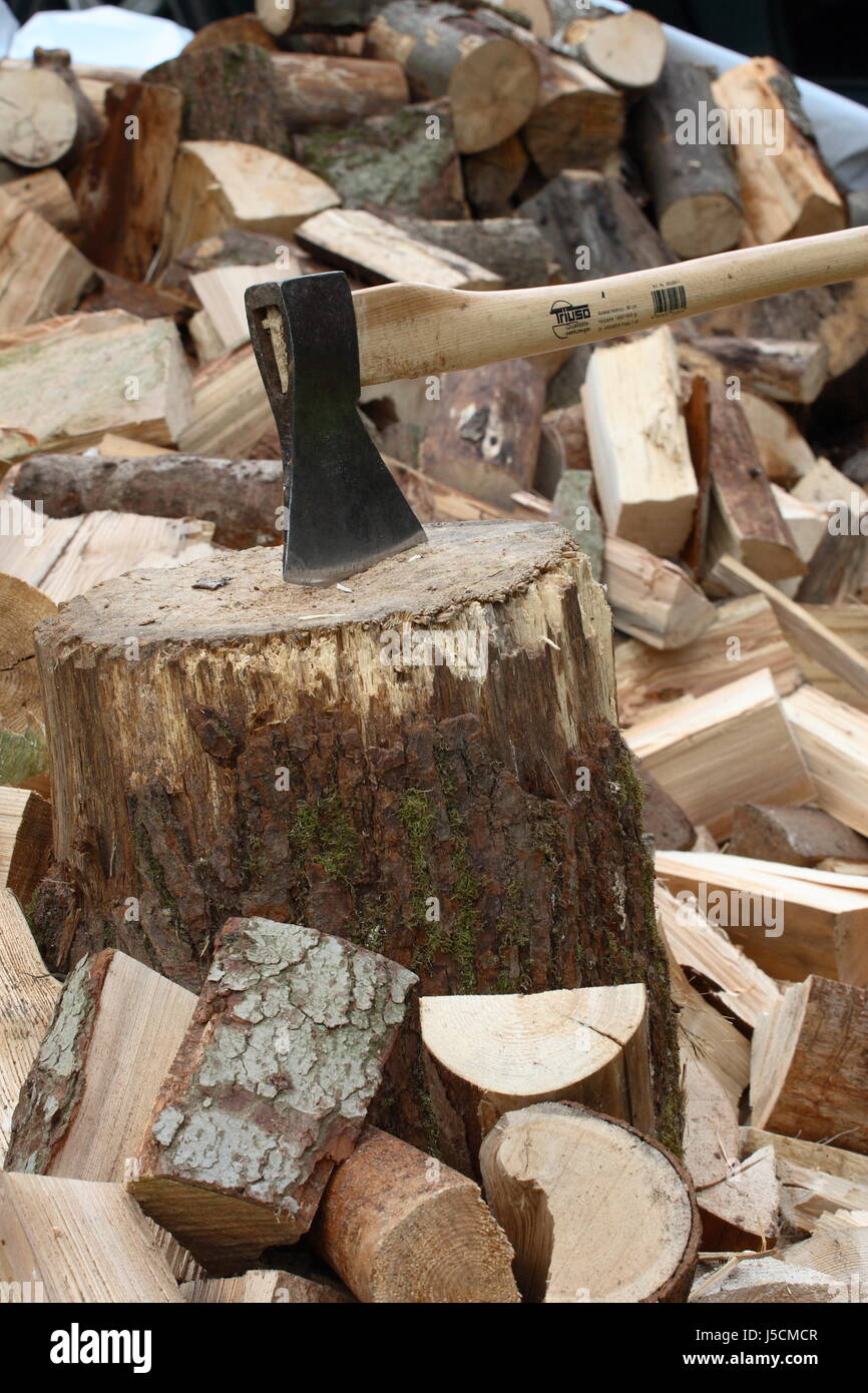 axe in chopping block in front of piles of logs Stock Photo - Alamy