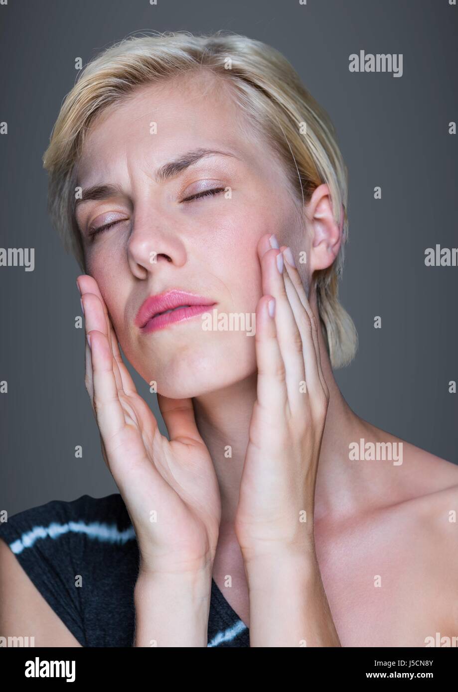 Digital composite of Close up of woman rubbing face against grey ...