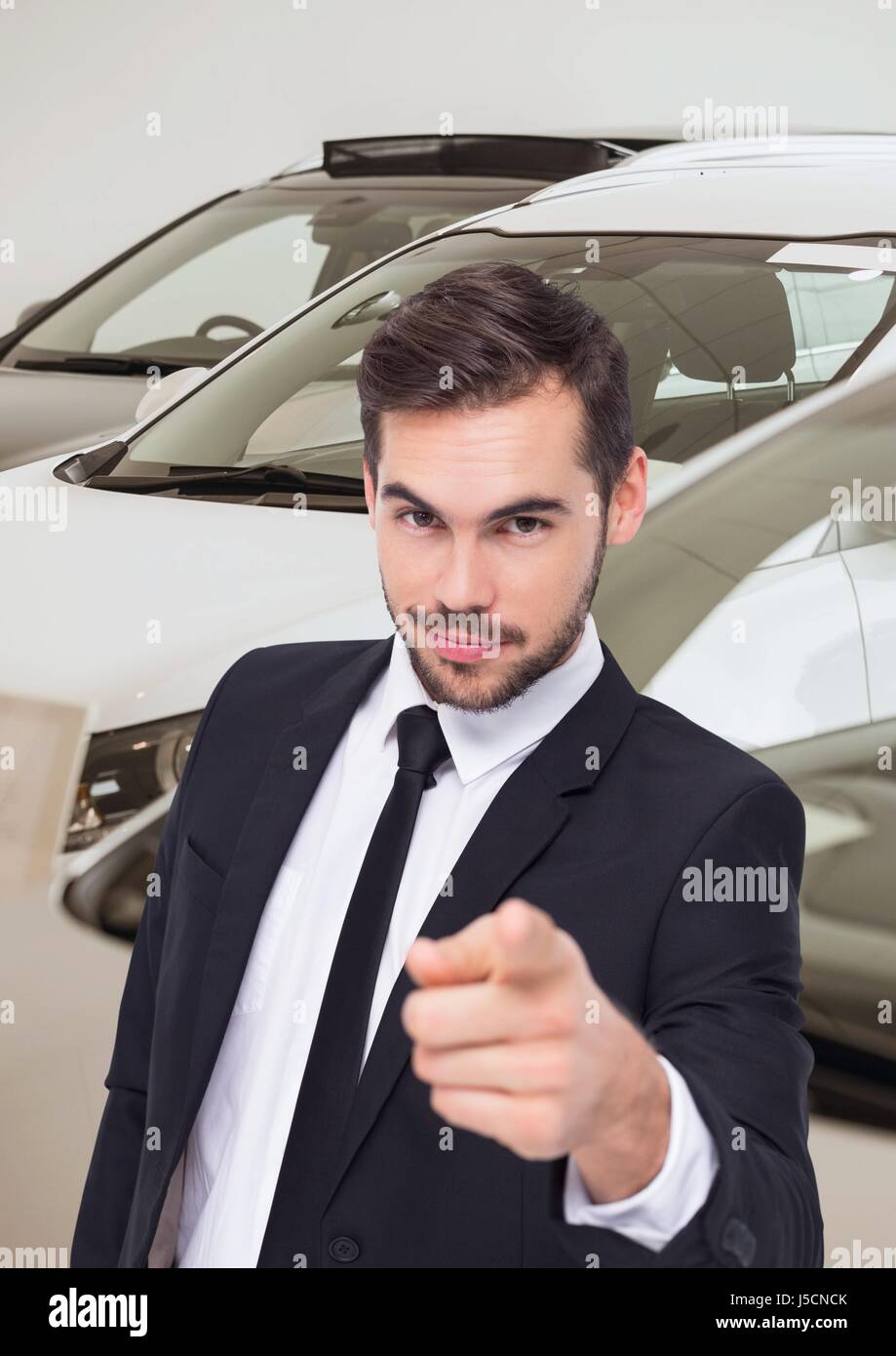 Digital composite of Salesman pointing against cars in showroom Stock ...