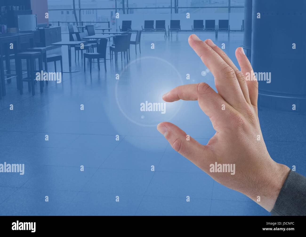 Digital composite of Hand Touching air of spacious room with many seats ...