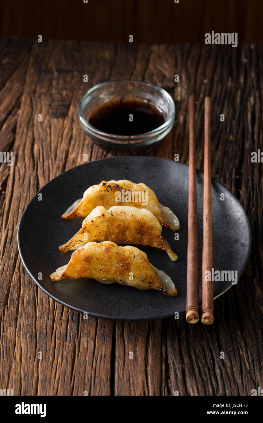 A plate of Japanese gyoza dumplings sitting on a rustic wooden table ...