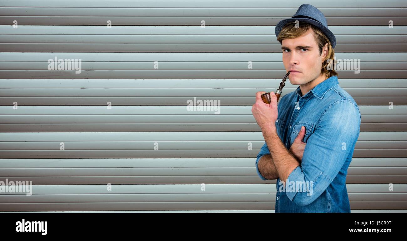 Digital composite of Confident hipster smoking pipe against wall Stock ...