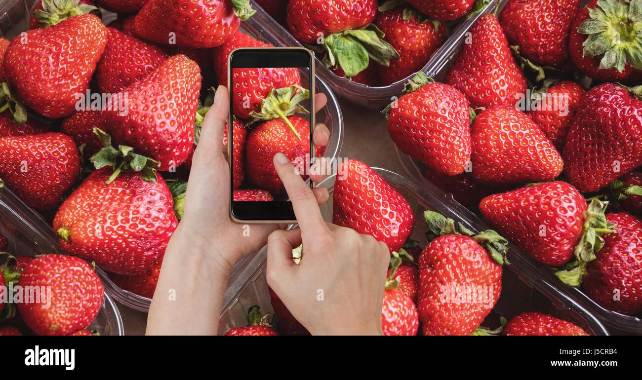 Digital composite of Hand photographing strawberries through smart ...